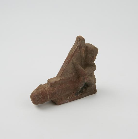 Solid terracotta figure of seated male playing a harp propped on his ...