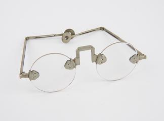 Chinese spectacles with round flat pebble lenses in a rimless frame and ...