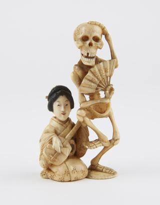 Statue depicting skeleton dancing and woman playing instrument ...