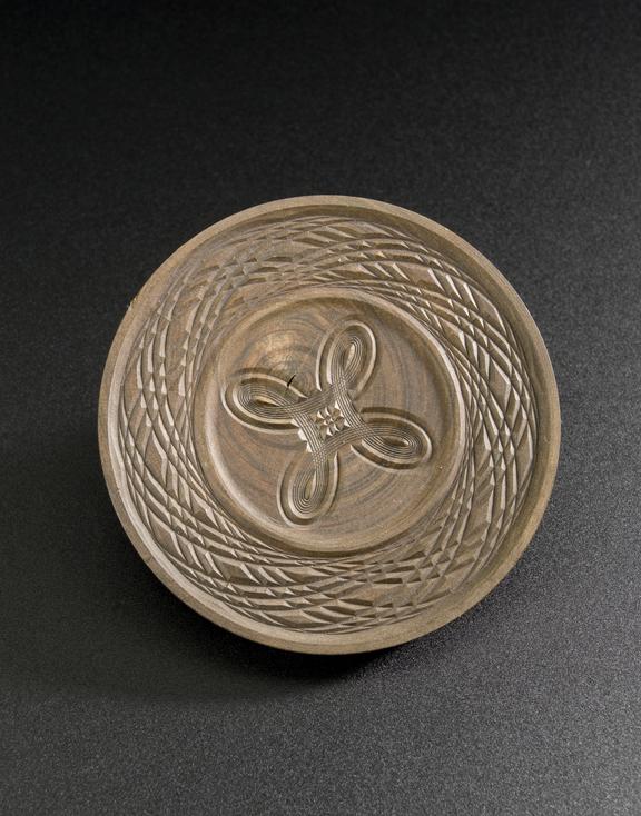 Wood disc with designs on one side, and a fine textured surface on the ...