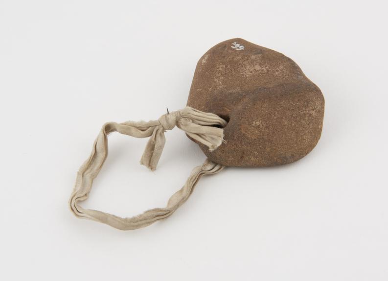 Gritstone pebble or witch stone perforated with white cloth sling ...