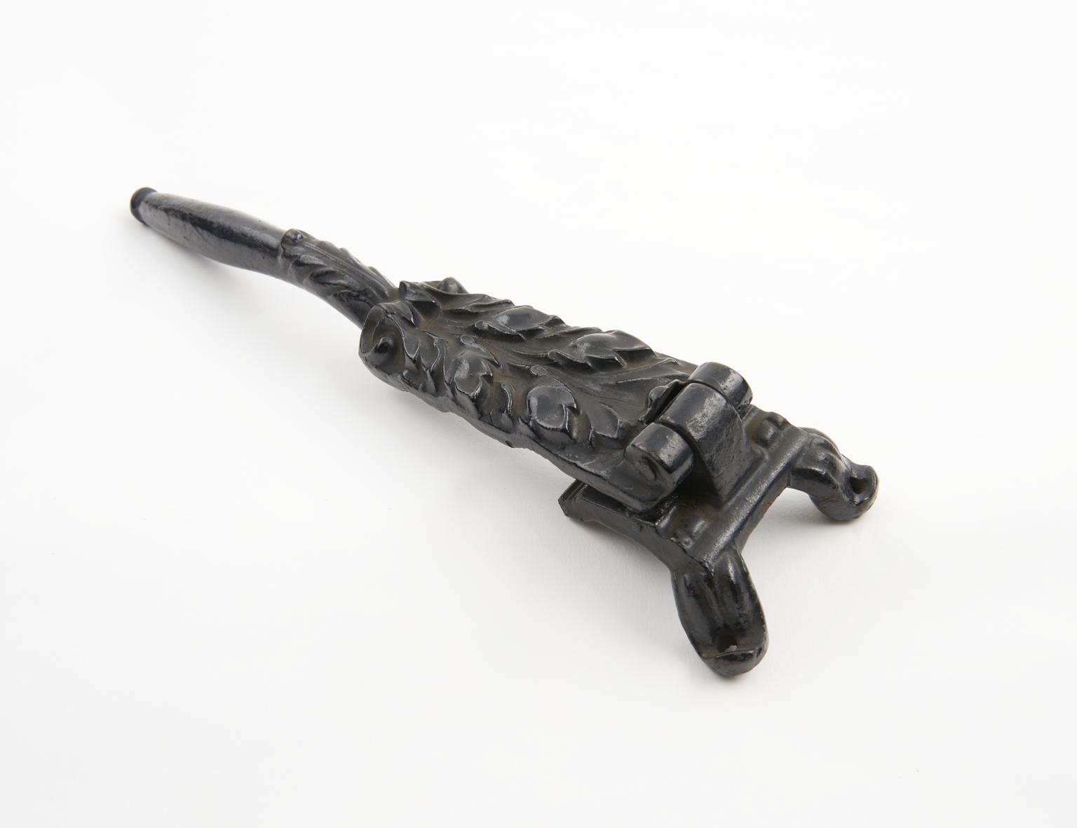 Cast iron cork-compressor with decorative foliate design on handle and ...