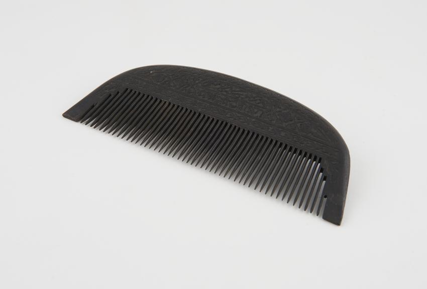 Wide-toothed, black, wooden comb with curved handle decorated with ...