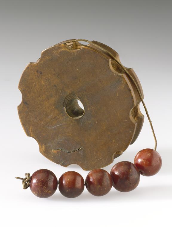 Grooved disc with five spherical beads attached by a thread | Science ...