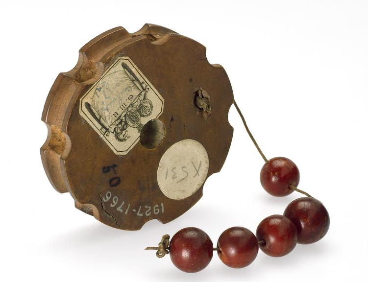 Grooved disc with five spherical beads attached by a thread | Science ...